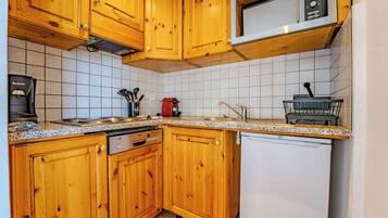 Cozinha com armários de madeira, micro-ondas, cafeteira e lava-louças.
