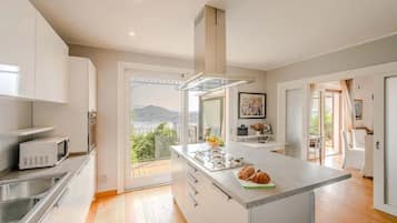 Uma cozinha moderna com uma ilha grande, eletrodomésticos de aço inoxidável e vista para o exterior.