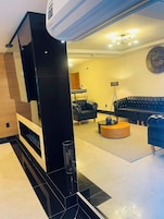 Uma sala de estar moderna com um sofá preto, uma mesa de centro redonda e um espelho grande.