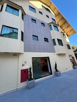 Um hotel de vários andares com fachada moderna, grandes janelas e uma porta vermelha.