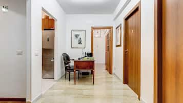 Um corredor com porta de madeira, um quadro na parede e uma mesa com uma cadeira.