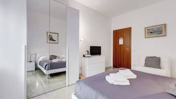 Um quarto moderno com uma cama, uma televisão, uma escrivaninha e um guarda-roupa.