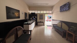 Um saguão de hotel com balcão de recepção, área de estar e vista para a rua.