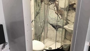 Casa de banho com sanita, bidé e cabine de duche em vidro.