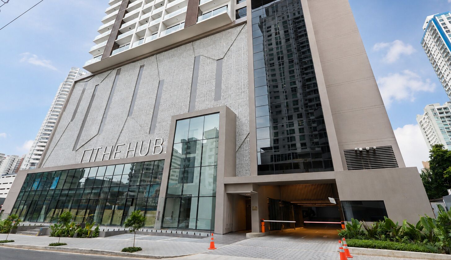 Um edifício de hotel moderno com fachada de vidro marcante e o nome 'THE HUB' exibido.