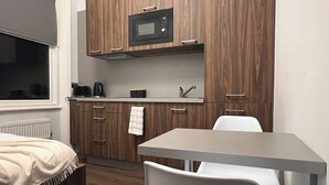Uma cozinha compacta com armários de madeira, micro-ondas, pia e um pequeno espaço de refeições com mesa e cadeiras.