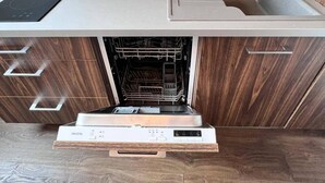 Uma cozinha compacta com máquina de lavar louça embutida, pia e bancada.