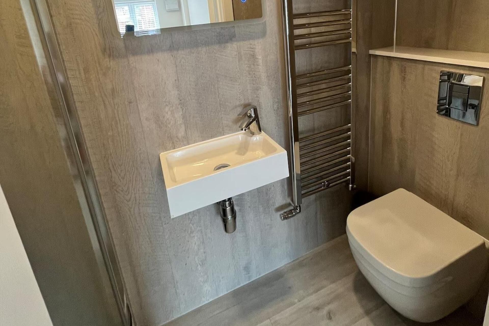 Uma casa de banho com uma sanita, um lavatório branco e um porta-toalhas.