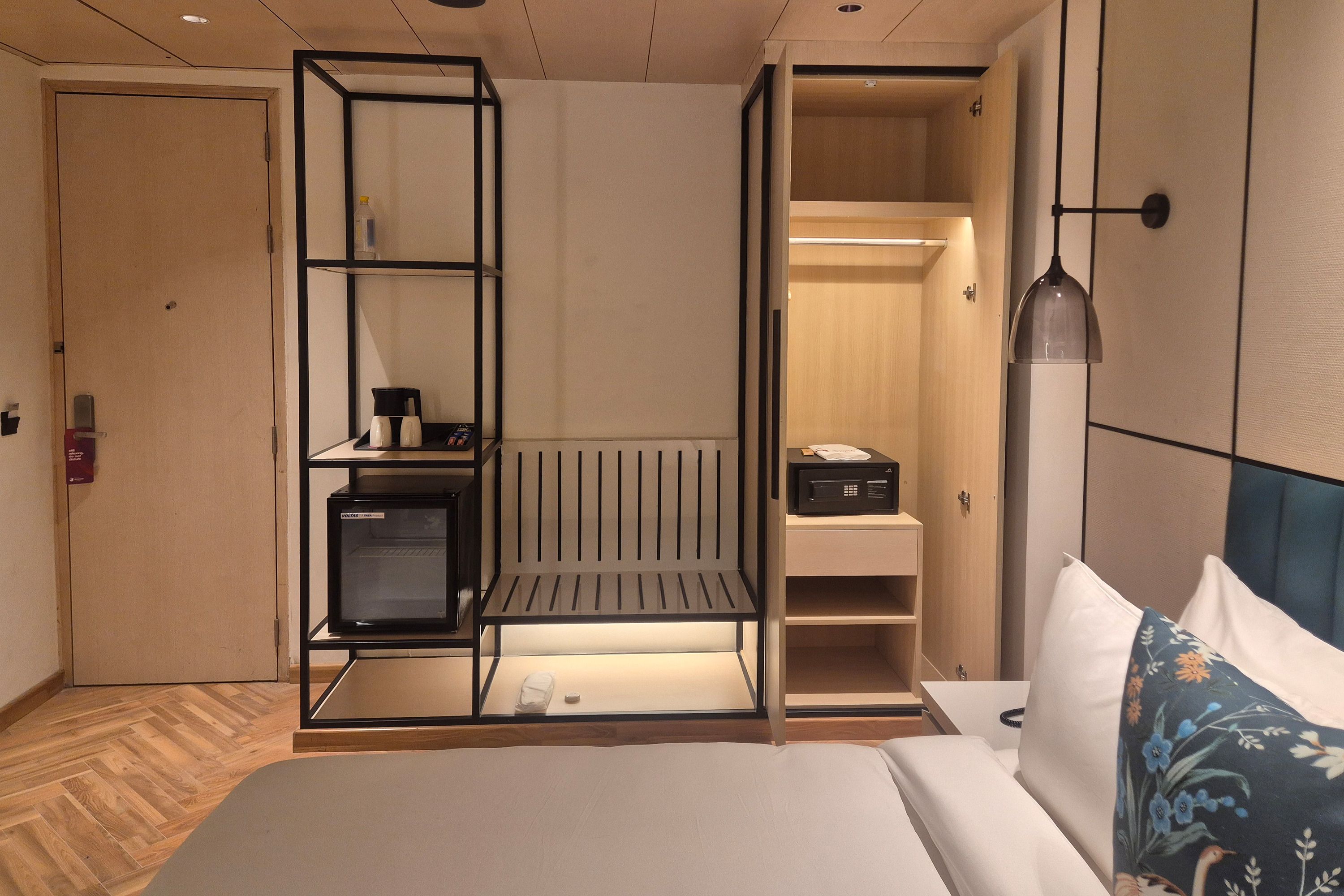 Quarto de hotel com cama, escrivaninha, guarda-roupa e radiador.