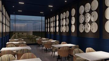 Interior de restaurante com mesas longas, cadeiras estampadas e pratos decorativos nas paredes.