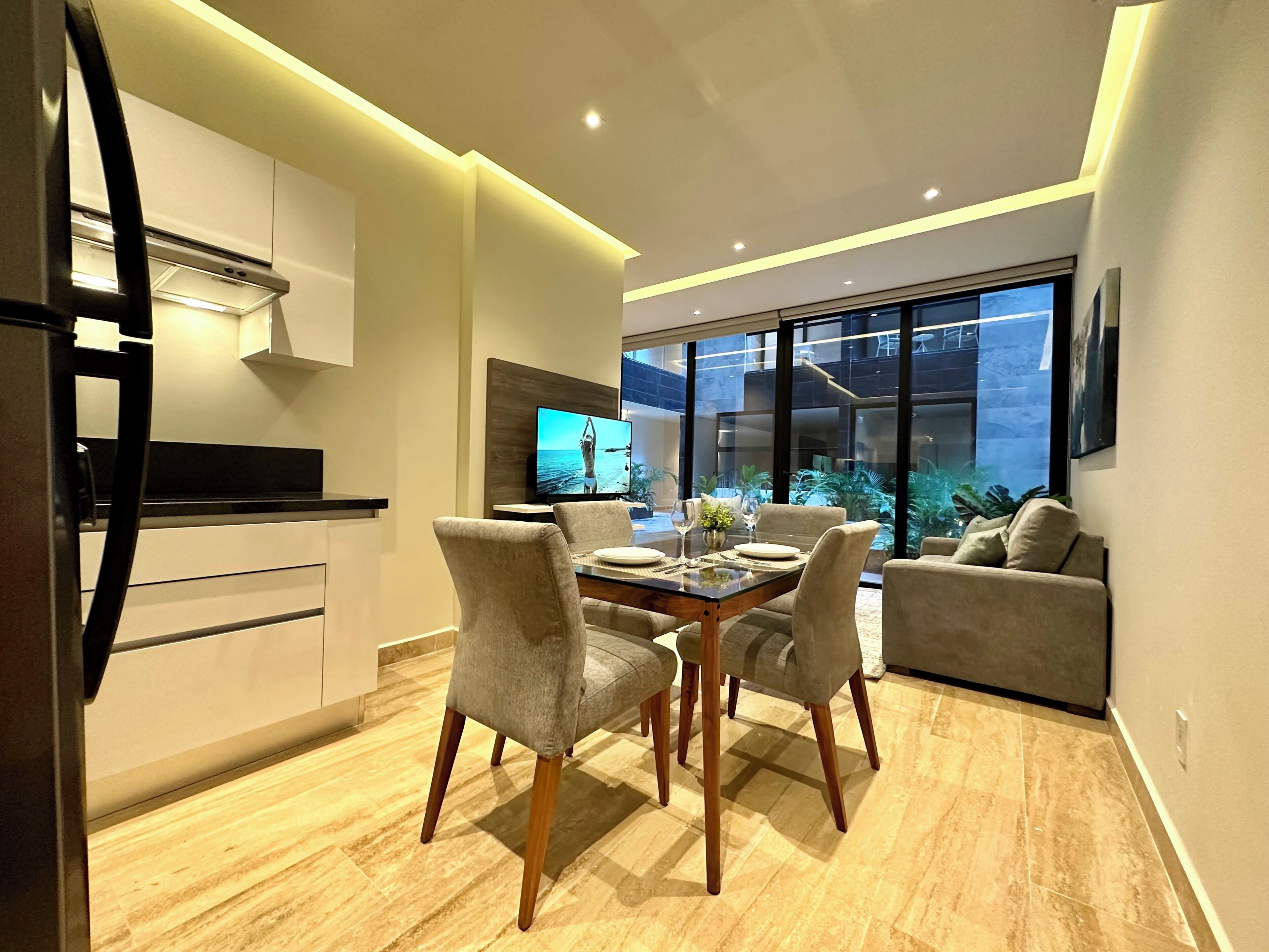 Cozinha moderna com área de refeições, TV e vista para o exterior.