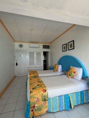 Quarto de hotel com duas camas, um guarda-roupa e uma porta.