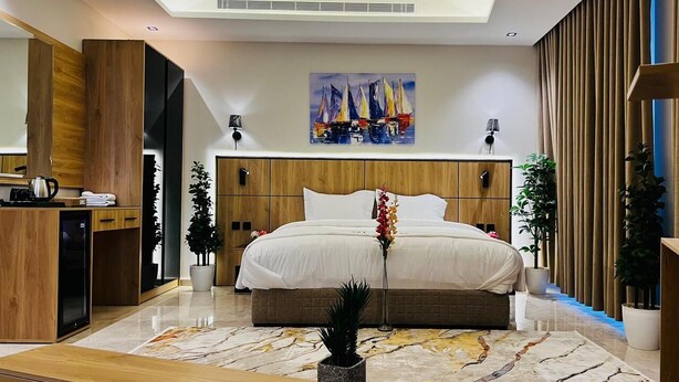 Quarto moderno com uma cama grande, cabeceira de madeira e um quadro de barcos à vela.