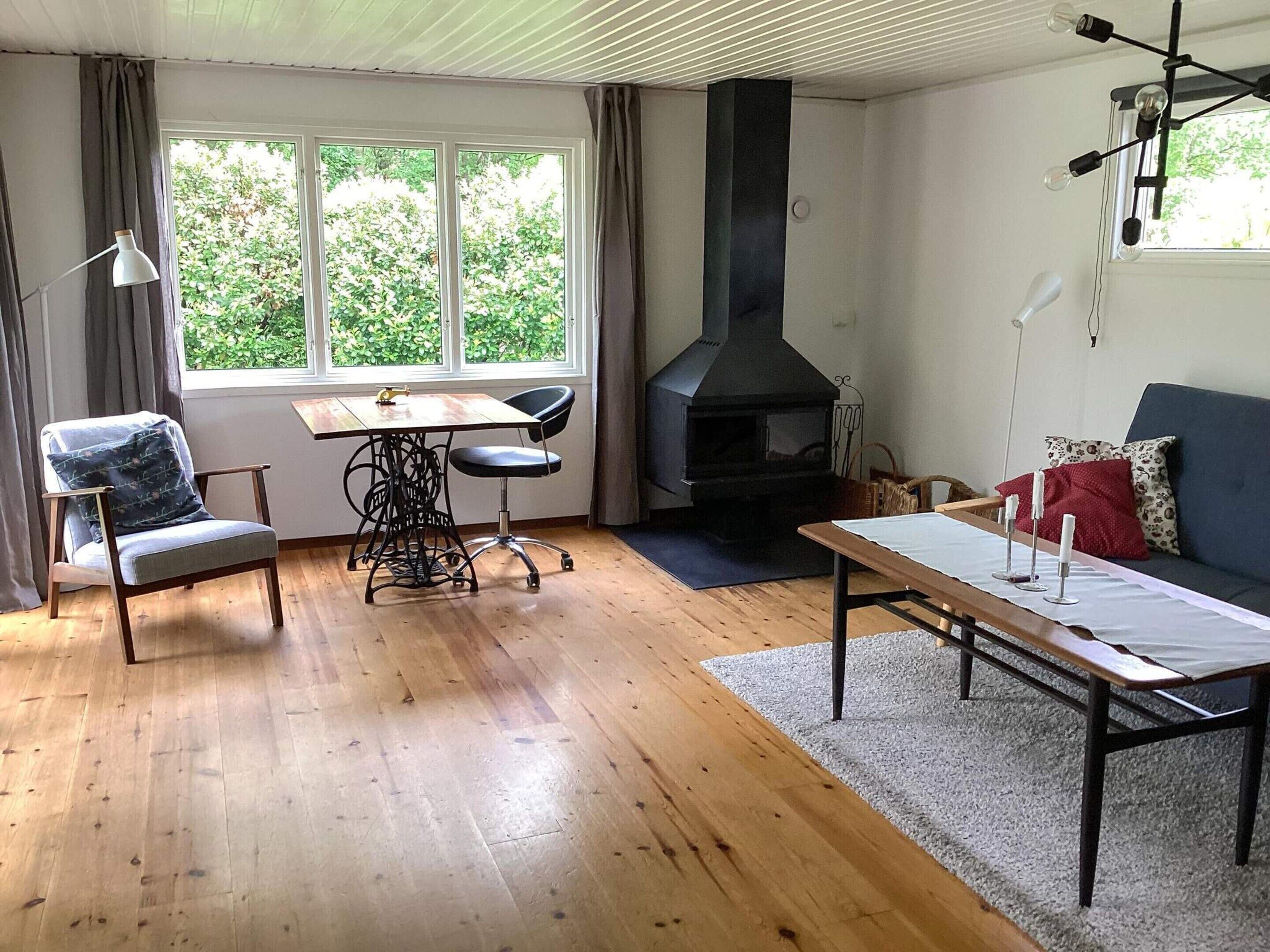 Uma sala de estar com lareira, mesa de jantar, sofá e uma poltrona.