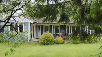 Uma casa com varanda, cercada por grama e árvores.
