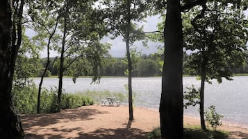 Um parque de campismo à beira do lago, com mesas de piquenique e vista desobstruída para a água.