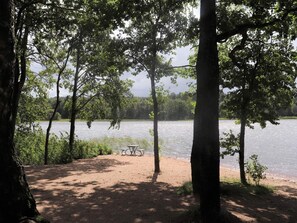 Um camping à beira do lago com mesa de piquenique e banco.