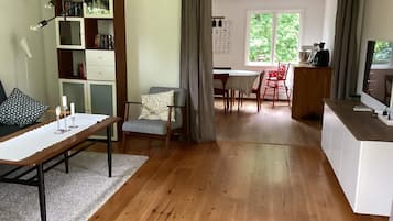 Quarto com uma mesa de jantar, uma cadeira, uma estante de livros, uma televisão e uma janela.