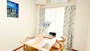 Uma sala de jantar com uma mesa de madeira, cadeiras, um vaso com flores e um quadro na parede.