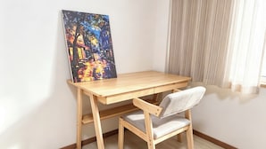 Uma mesa de madeira com uma cadeira em um quarto com janela e cortina.