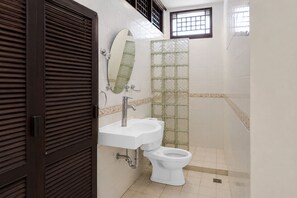Casa de banho com sanita, lavatório e espelho.