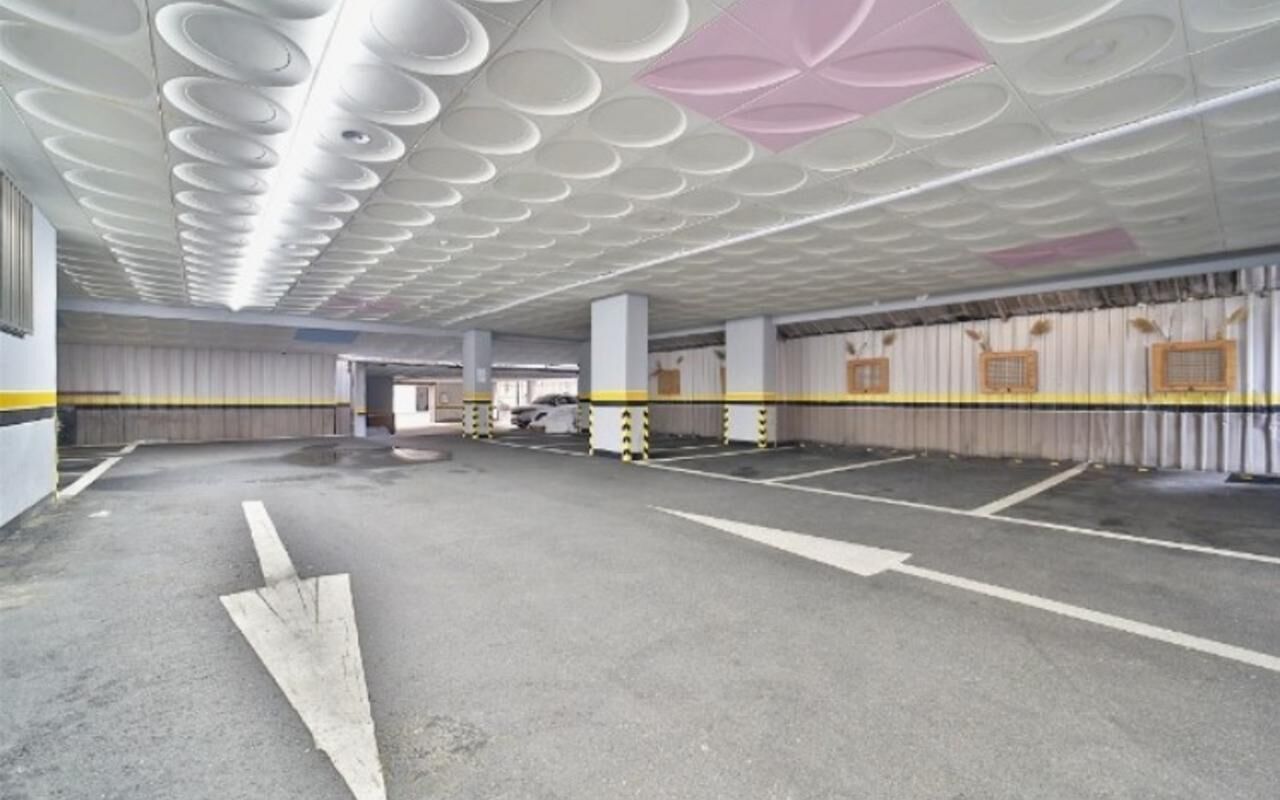 Garagem de estacionamento interna com painéis de teto brancos, piso de concreto e paredes com listras amarelas.