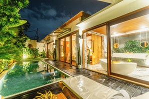 Um hotel moderno com piscina infinita, deck de madeira e uma banheira grande interna.