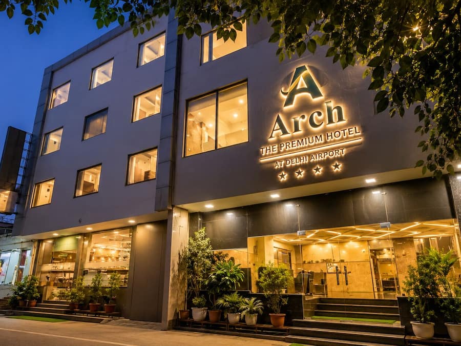 Um hotel com um grande letreiro 'Arch', várias janelas e uma entrada bem iluminada.