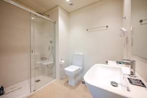 Uma casa de banho moderna com chuveiro em cabine de vidro, sanita e lavatório com espelho.