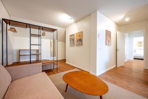 Um interior moderno com um sofá, uma mesa de madeira, uma escada e prateleiras fixadas na parede.