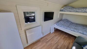 Quarto pequeno com beliche, janela com vista, radiador e um cantinho para sentar.