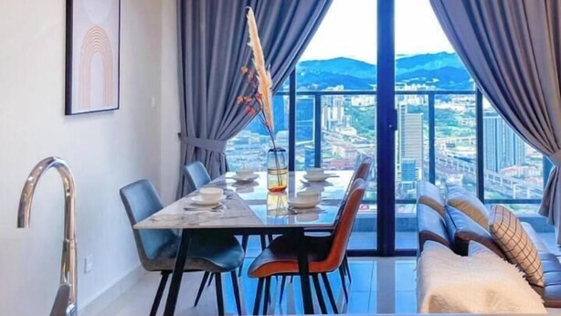 Uma área de refeições moderna com uma mesa, cadeiras e vista para a cidade através de grandes janelas.