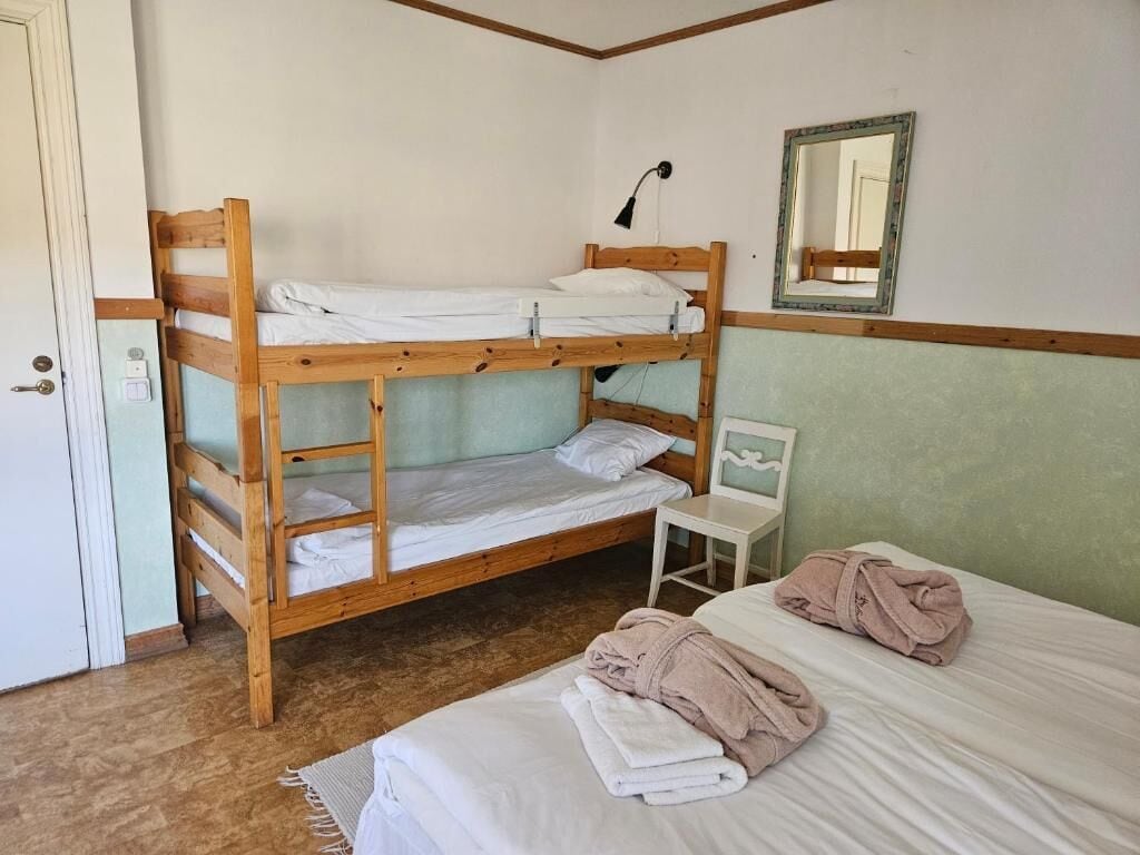 Quarto com beliche, escrivaninha, espelho e toalhas.