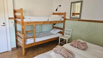 Quarto com beliche, escrivaninha, espelho e toalhas.