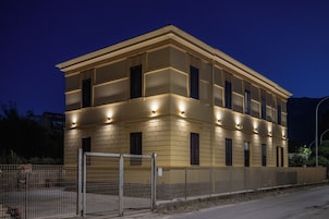 Um edifício de vários andares com fachada simétrica, janelas uniformemente distribuídas e entrada com portão.