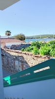 Vista costeira com turbinas eólicas, um muro de pedra e vegetação.