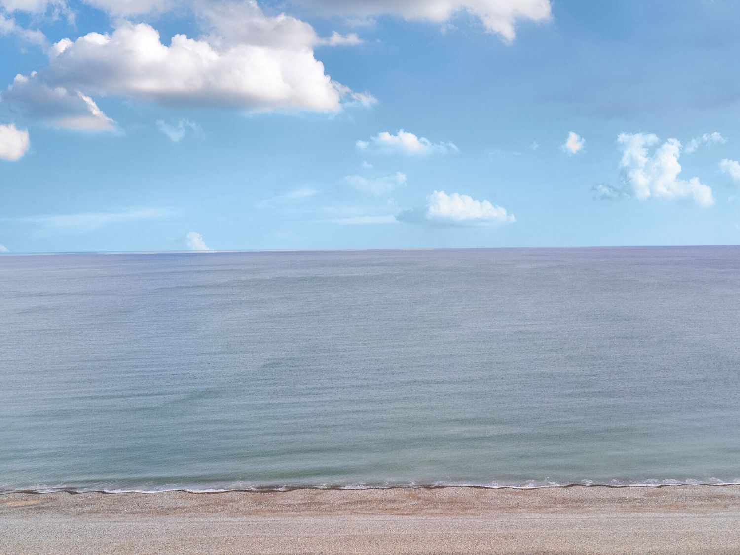 Uma praia com céu claro e mar calmo.
