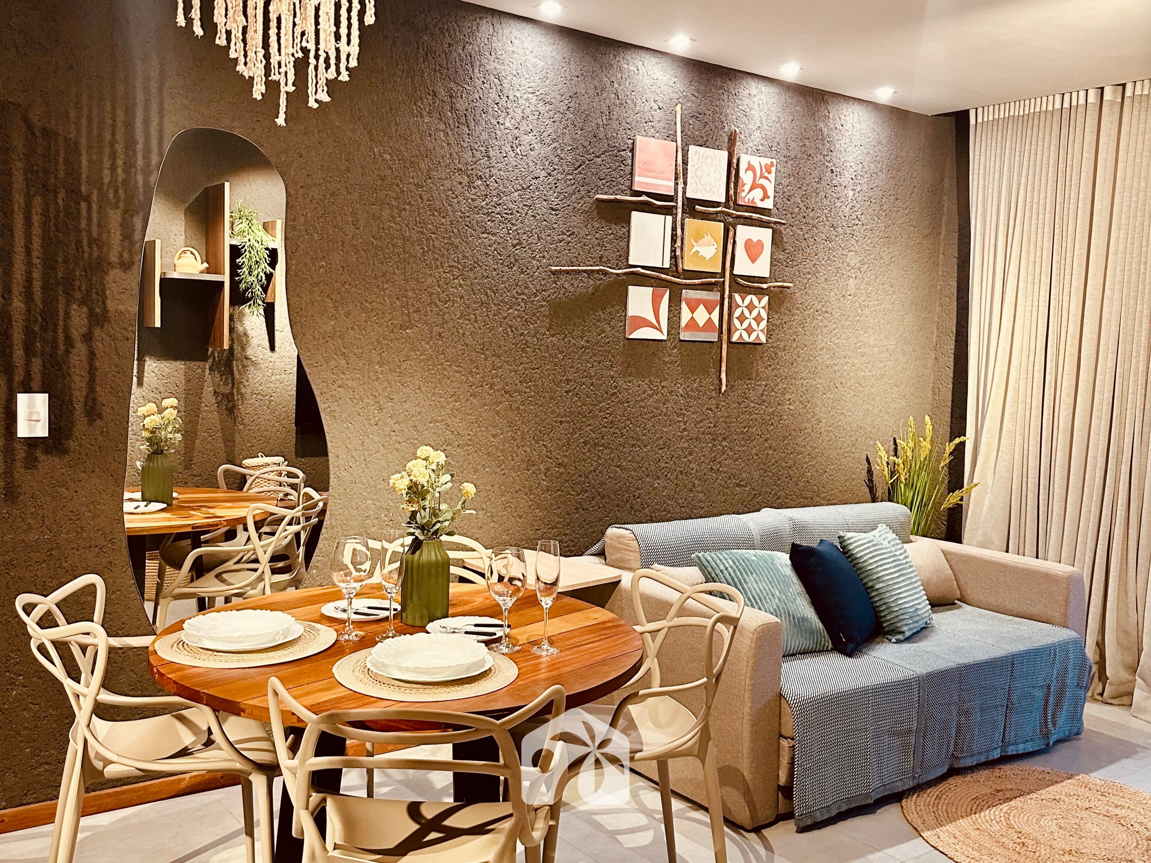 Uma sala de estar moderna com área de jantar, incluindo um sofá, cadeiras, uma mesa de jantar posta para quatro pessoas e uma prateleira com objetos decorativos.