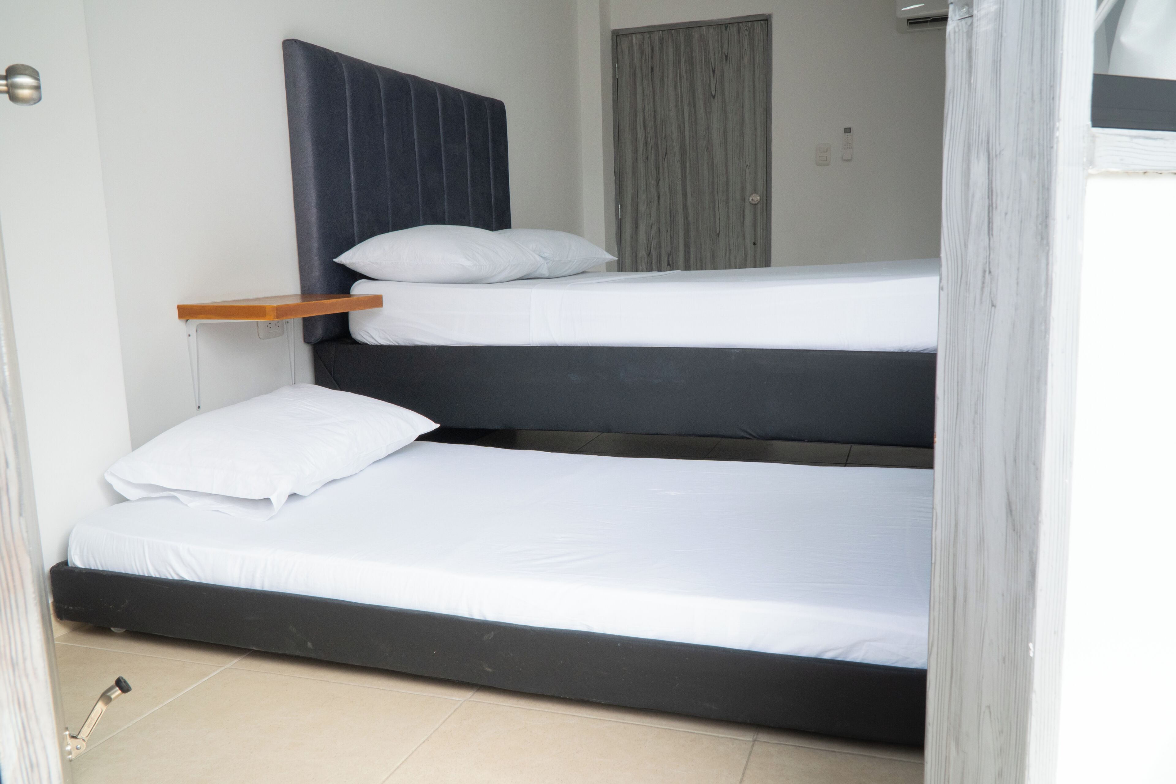 Um quarto com uma cama beliche, uma prateleira de madeira e uma porta.