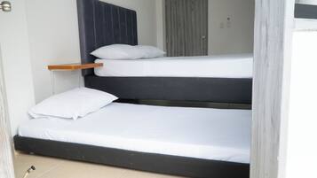 Um quarto com uma cama beliche, uma prateleira de madeira e uma porta.