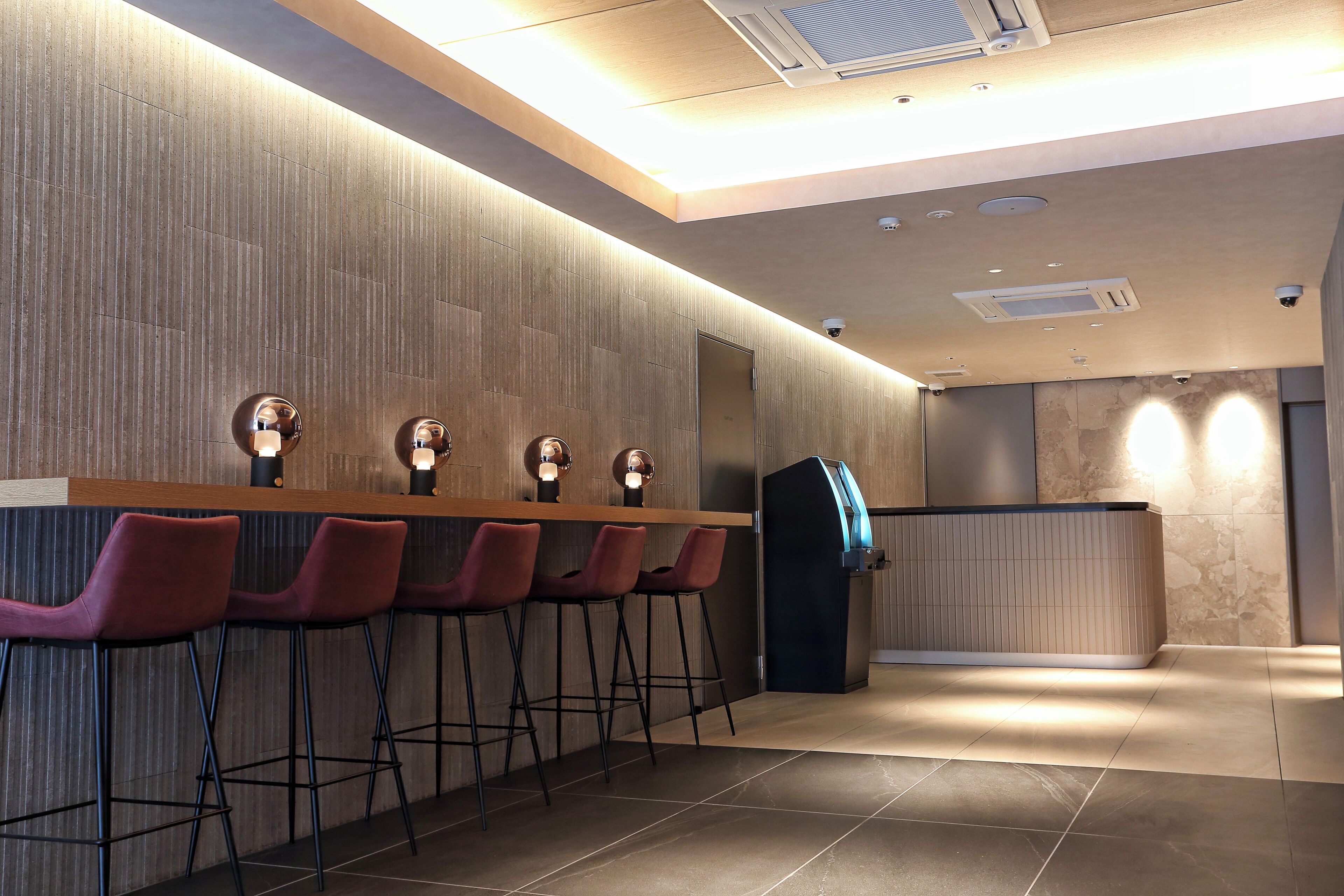 Uma área de bar moderna com banquetas, balcão e mesa de recepção.