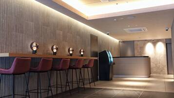 Uma área de bar moderna com banquetas, balcão e mesa de recepção.