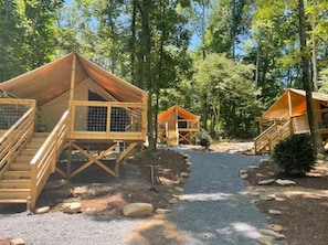 Um camping com cabanas de madeira, cada uma com uma escada e entrada cercada.