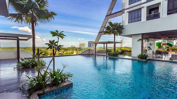 Uma piscina no terraço com palmeiras, vista para a paisagem urbana e uma estrutura de edifício moderna.