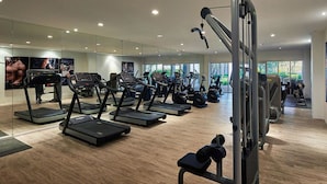 Uma academia com esteiras, elípticos e equipamentos de musculação.