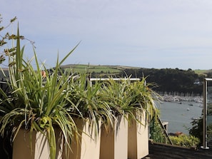 Varanda com vasos de plantas com vista para uma marina e barcos.