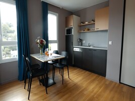 Uma cozinha moderna com uma mesa de jantar, cadeiras e vista para o exterior.