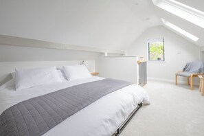 Quarto com uma cama, janela, radiador e uma cadeira.
