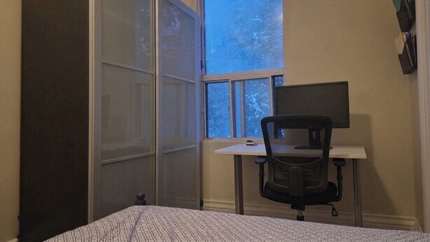 Quarto com cama, escrivaninha, cadeira, janela e guarda-roupa.