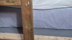 Uma cama beliche com escada de madeira, parede cinza e colchão branco.